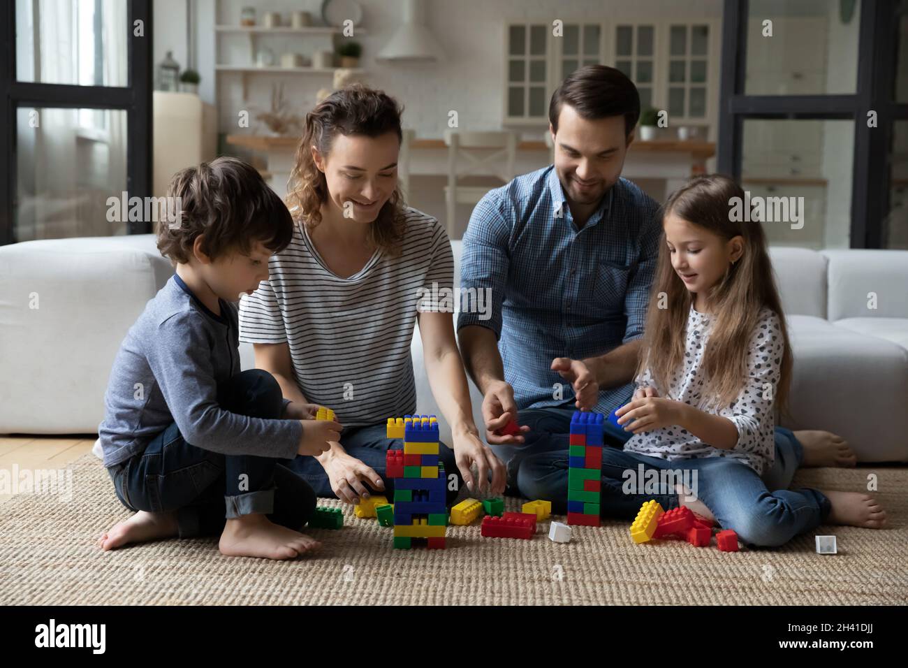 Happy young parents playing toys with small kids Stock Photo - Alamy