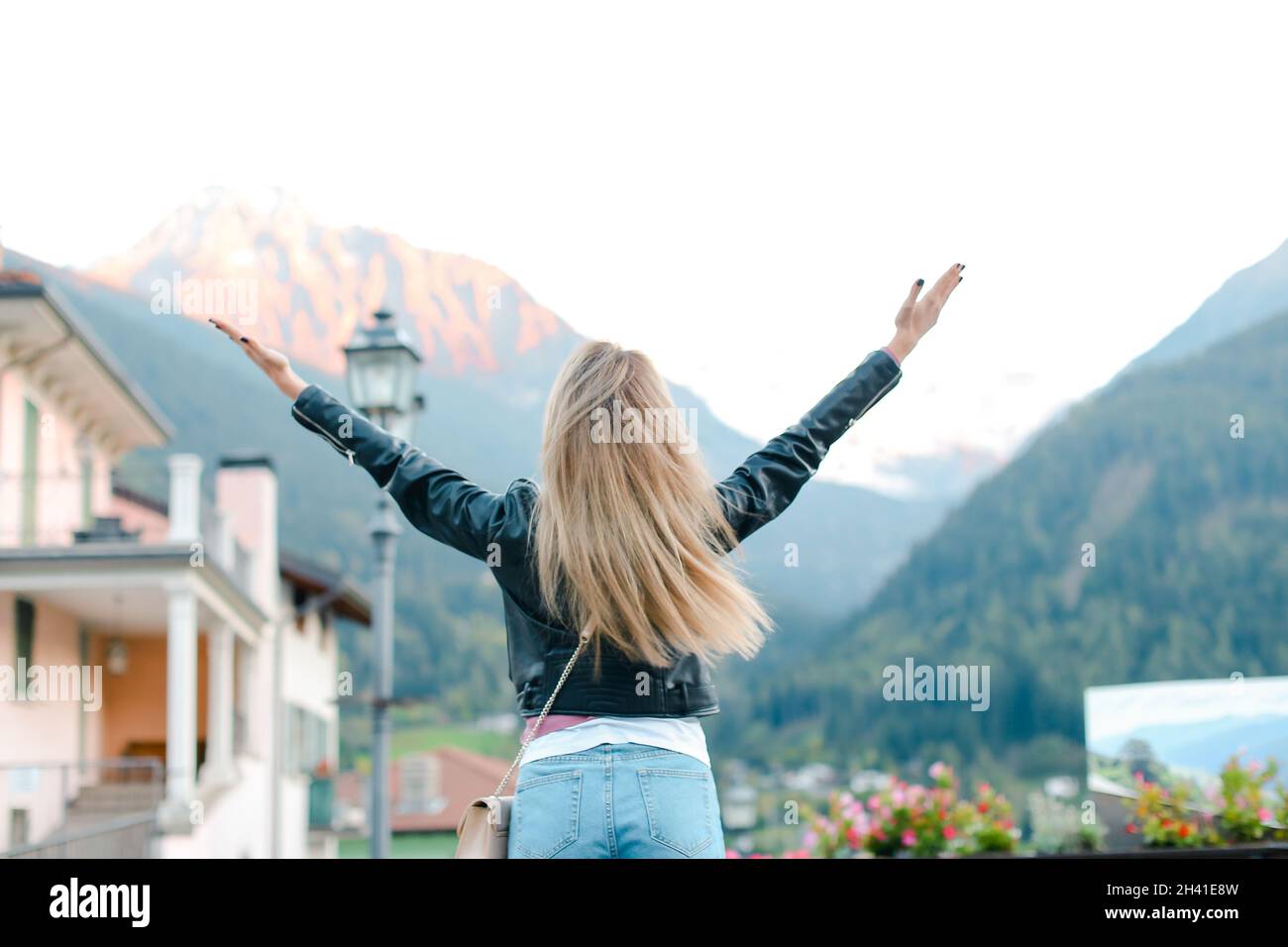 Back view of girl standing with raised hands in mountain village Stock ...