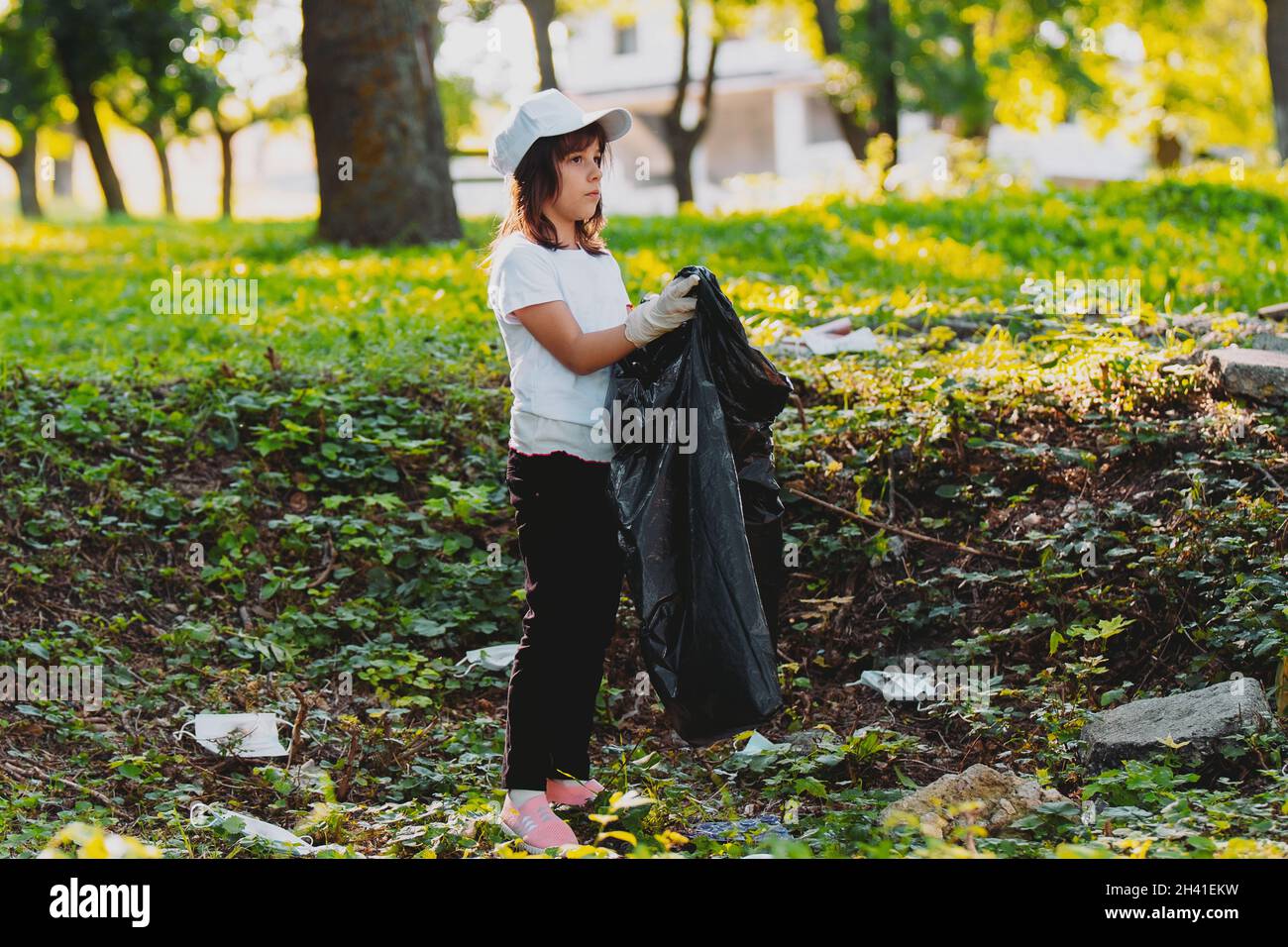 Side view photo of a young girl doing voluntary work outdoors in gloves ...