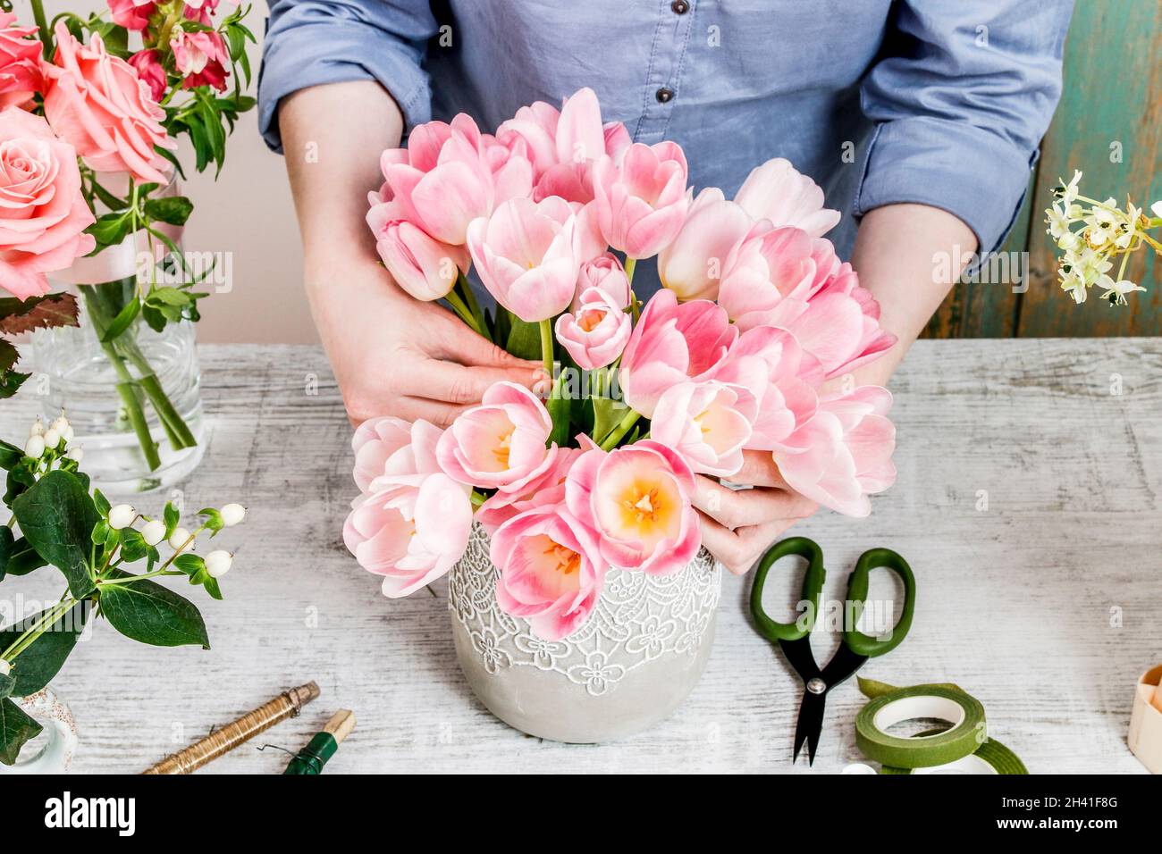 Florist at work: woman arranging flowers. Bouquet of pink tulips ...