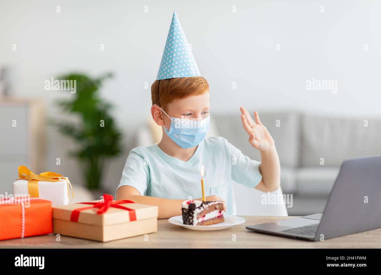 Boy in face mask and festive cap celebrating birthday Stock Photo - Alamy