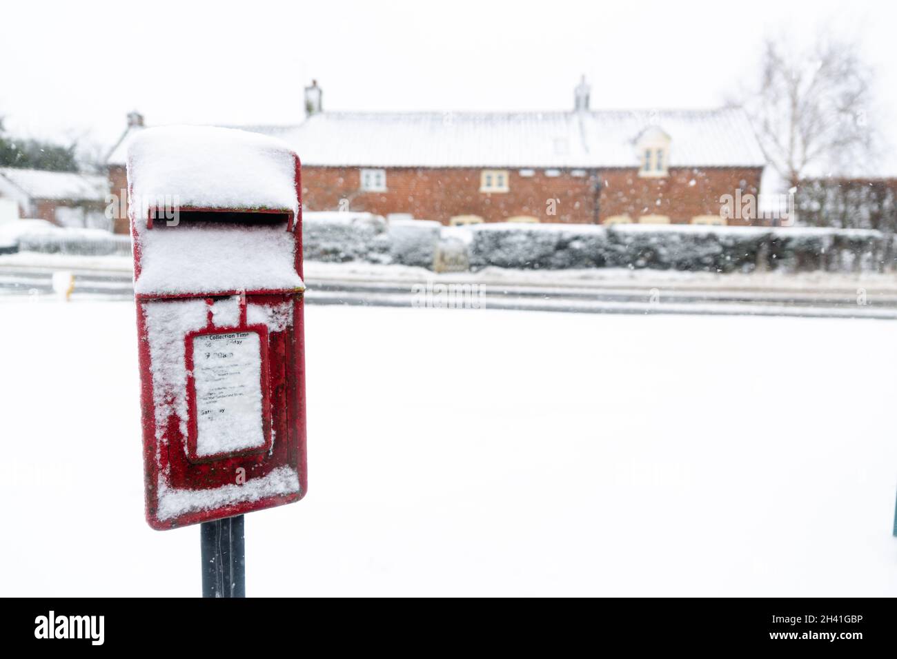 A red British post box covered in snow in a wintery snow covered ...