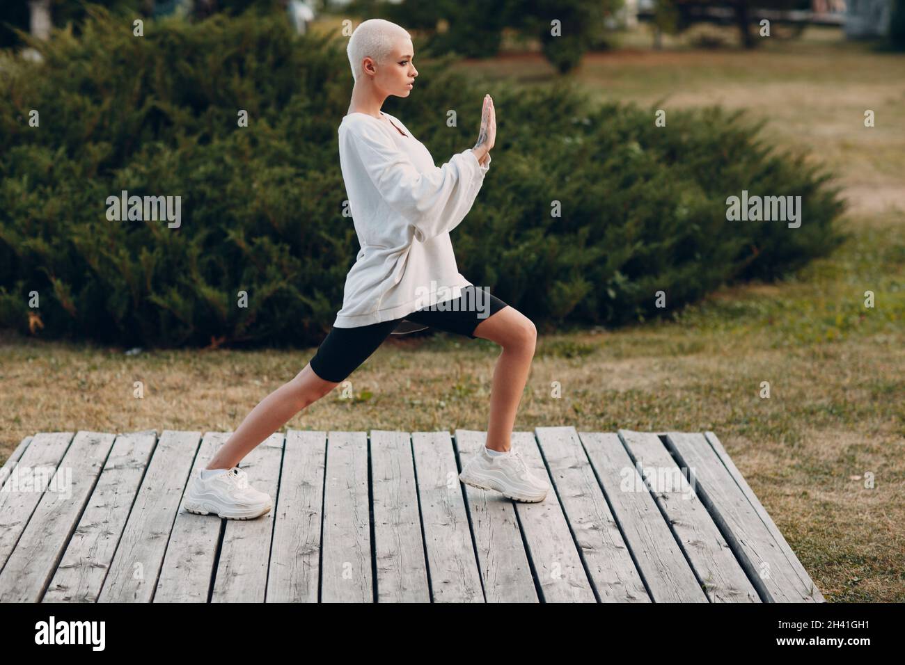 Millenial young woman blonde short hair outdoor doing Qigong Stock ...