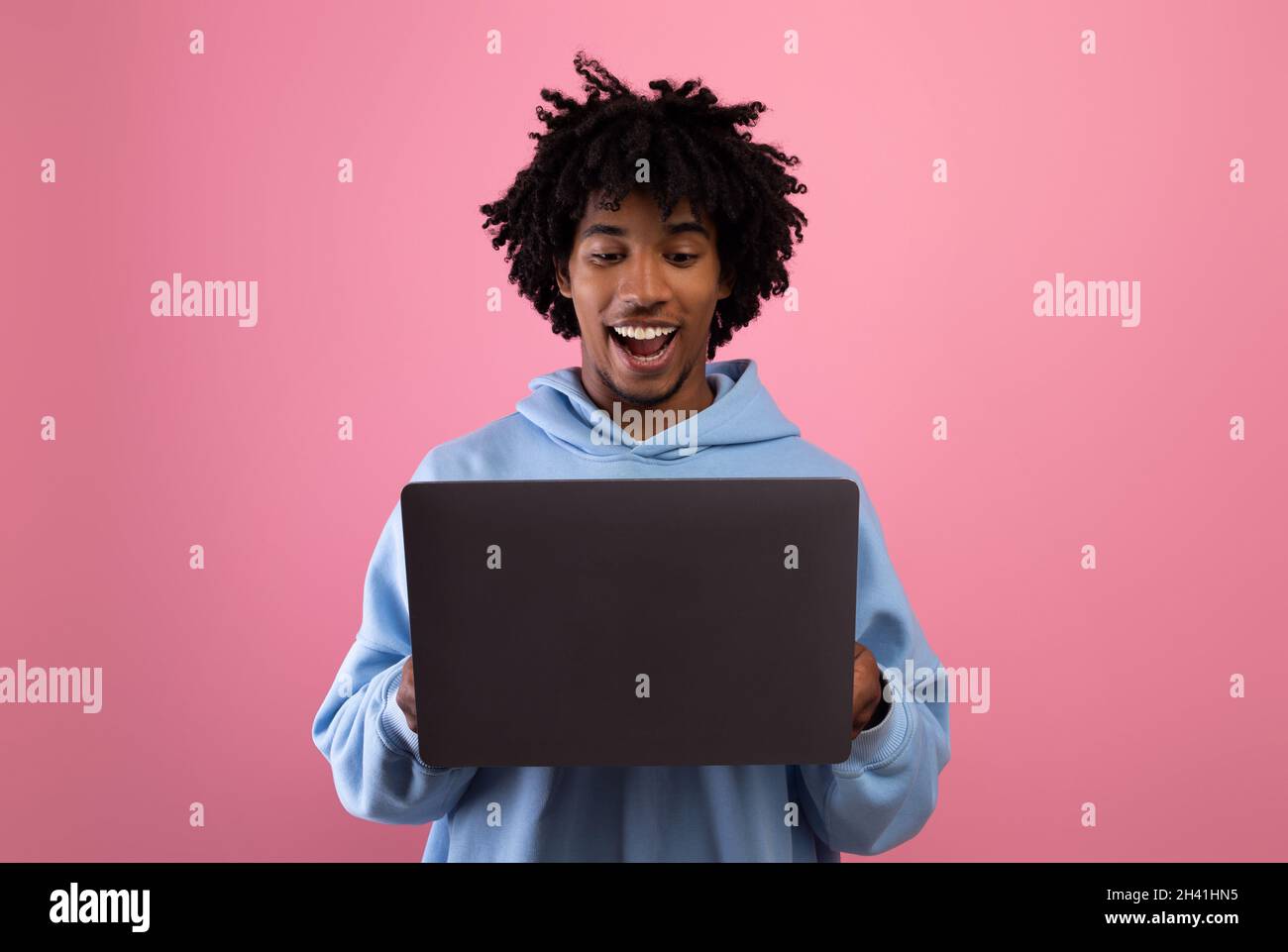 Happy black teenager looking at laptop screen with smile, watching ...