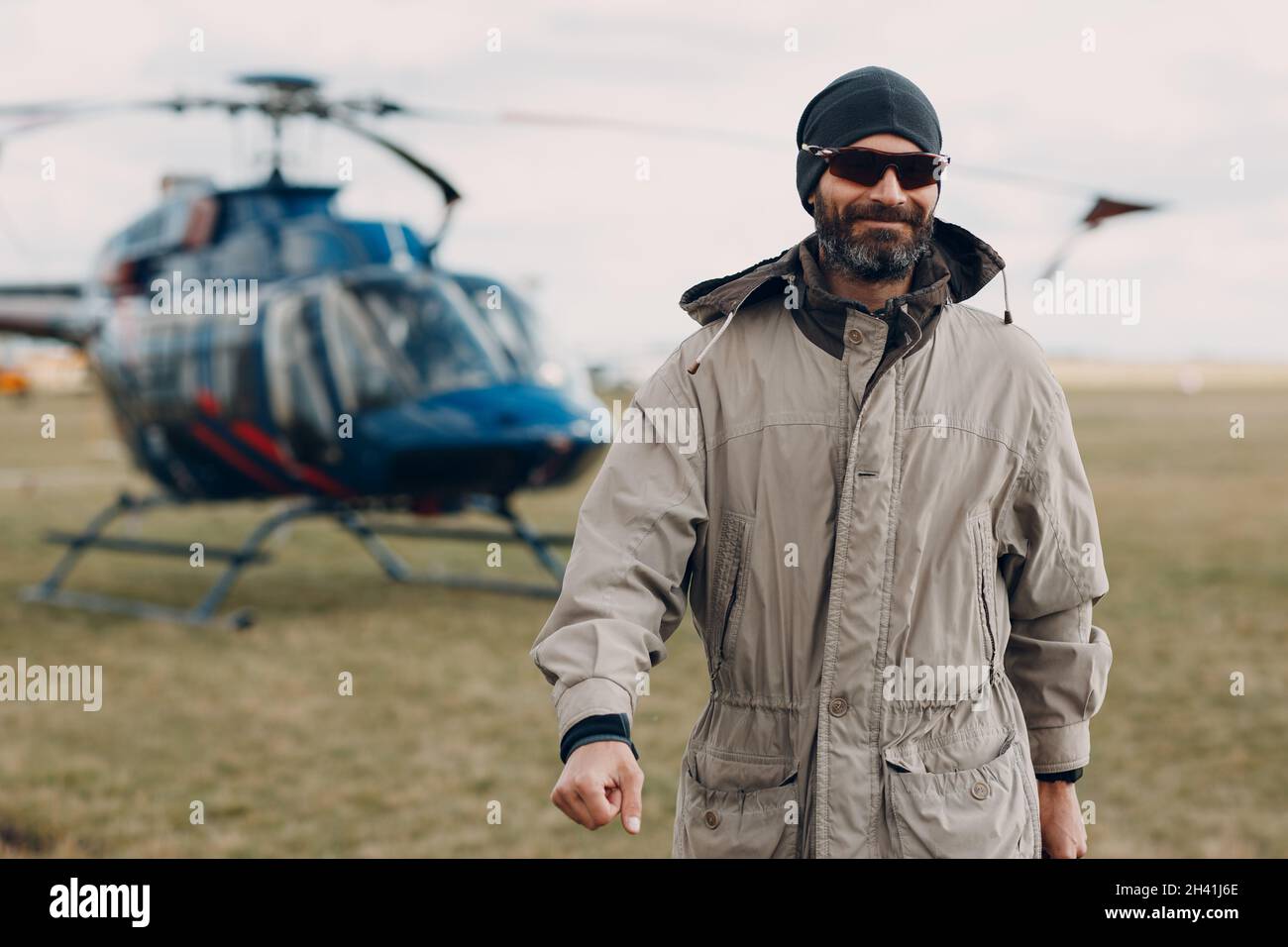 Portrait of helicopter pilot standing near vehicle in field airport ...