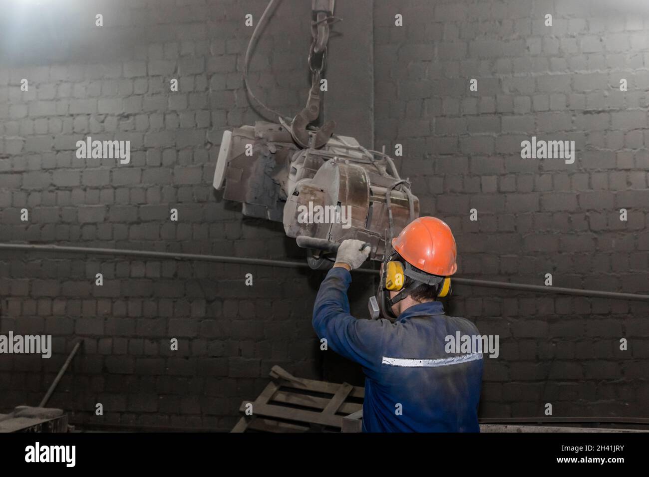 A working man in overalls, a protective helmet and a respirator ...
