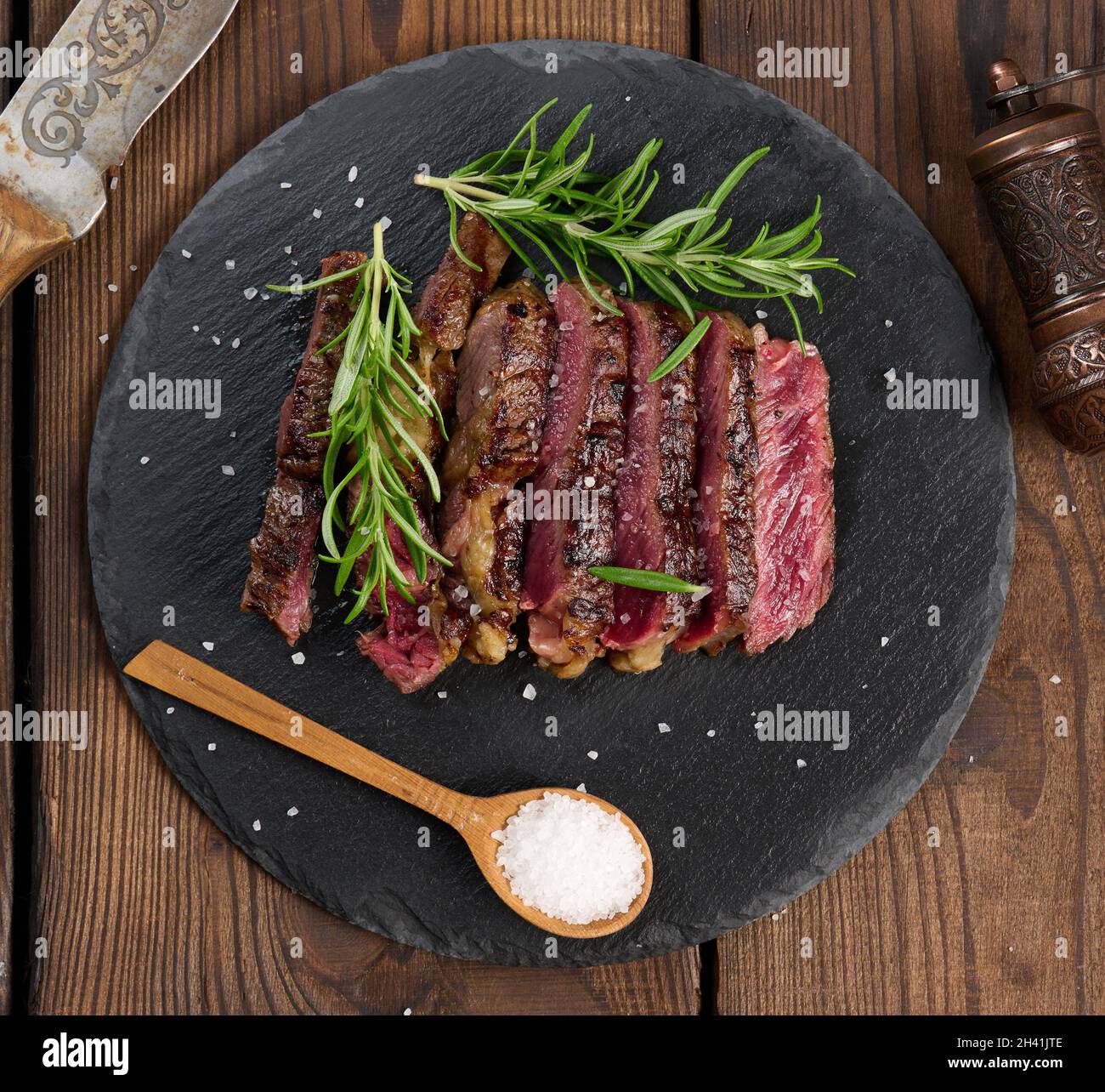 Fried piece of beef ribeye cut into pieces on a black board, rare ...