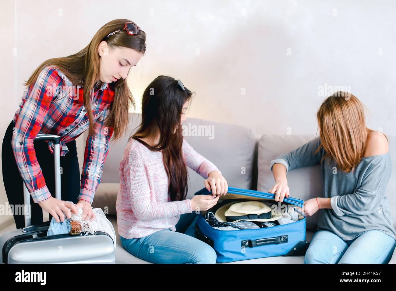 Cute girls going on trip and preparing suitcases on couch in afternoon ...