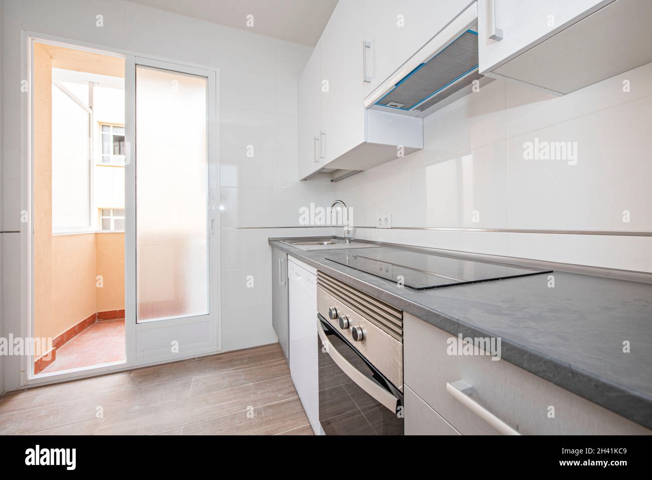 Kitchen with white and gray furniture and appliances with an exit door ...