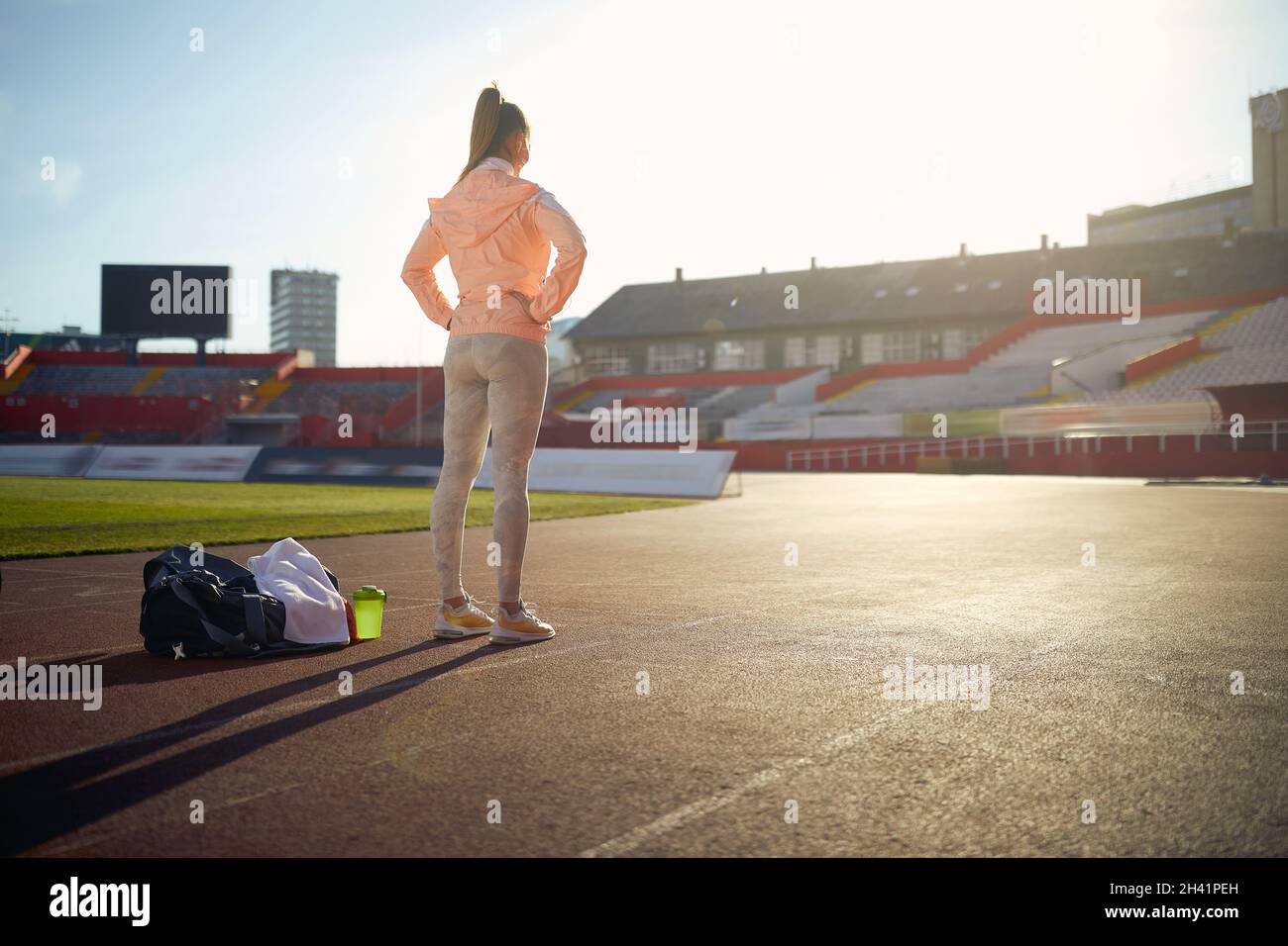 caucasian young female standing at the athletic track with hands on ...