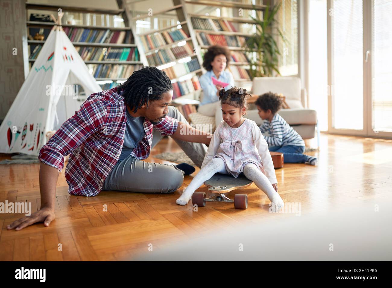 A young father likes spending time with his daughter playing in a relaxed atmosphere at home ...