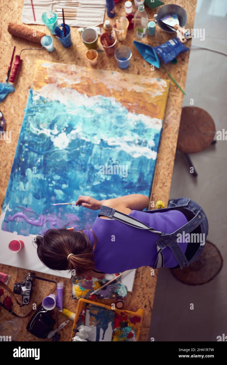 A bird's-eye view of a young female artist who paints in a creative ...