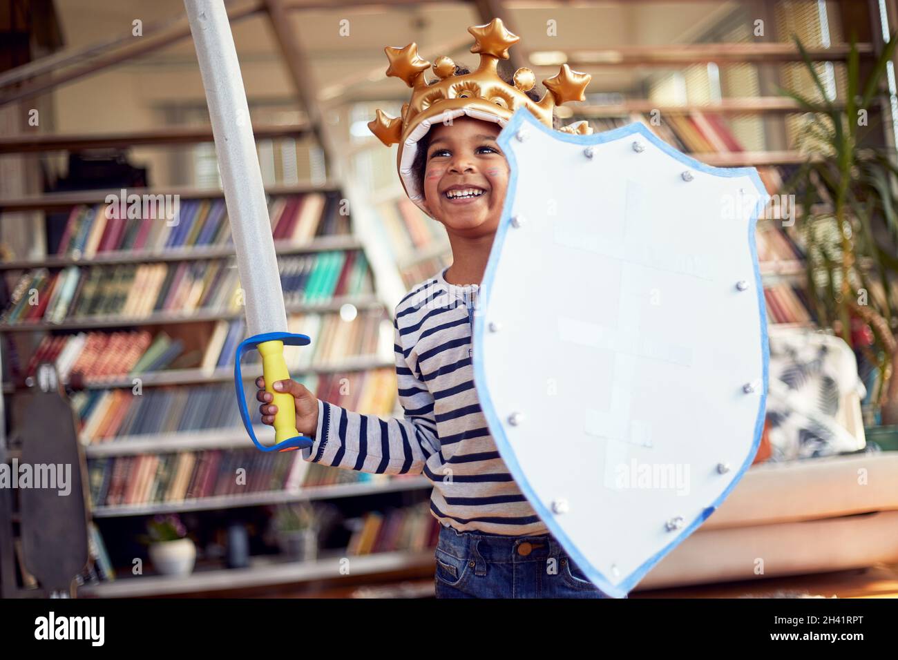A cheerful little boy dressed as knight is posing for a photo while ...