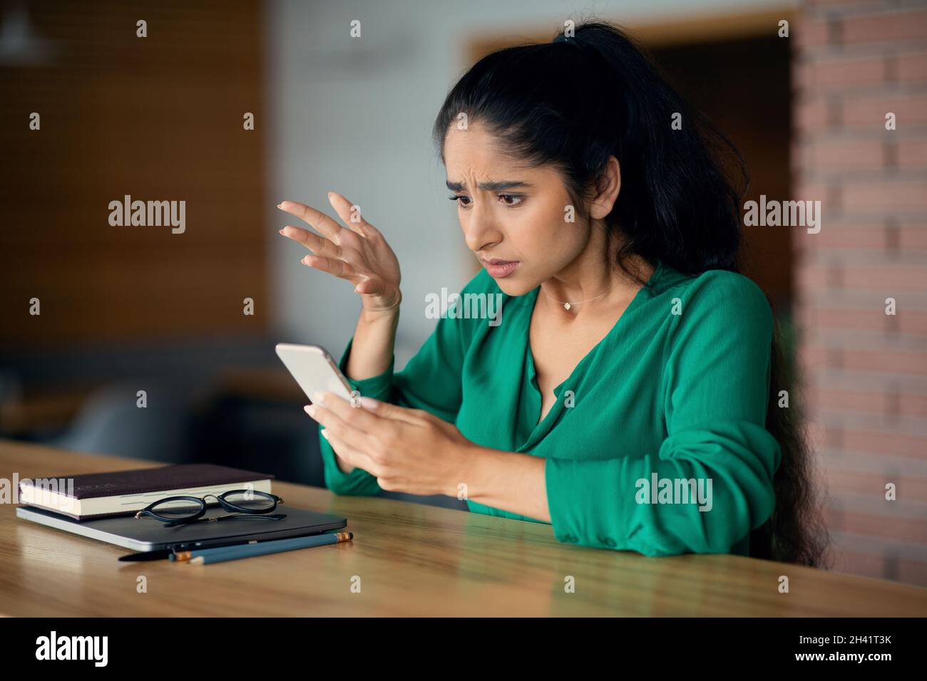 Emotional muslim lady using cellphone while working at cafe Stock Photo ...
