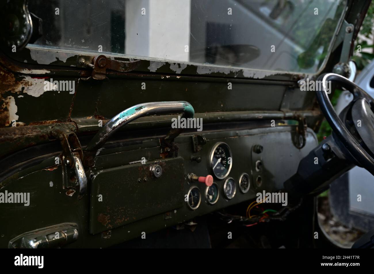 A close up shot inside an old car of the driving wheel, front glass ...