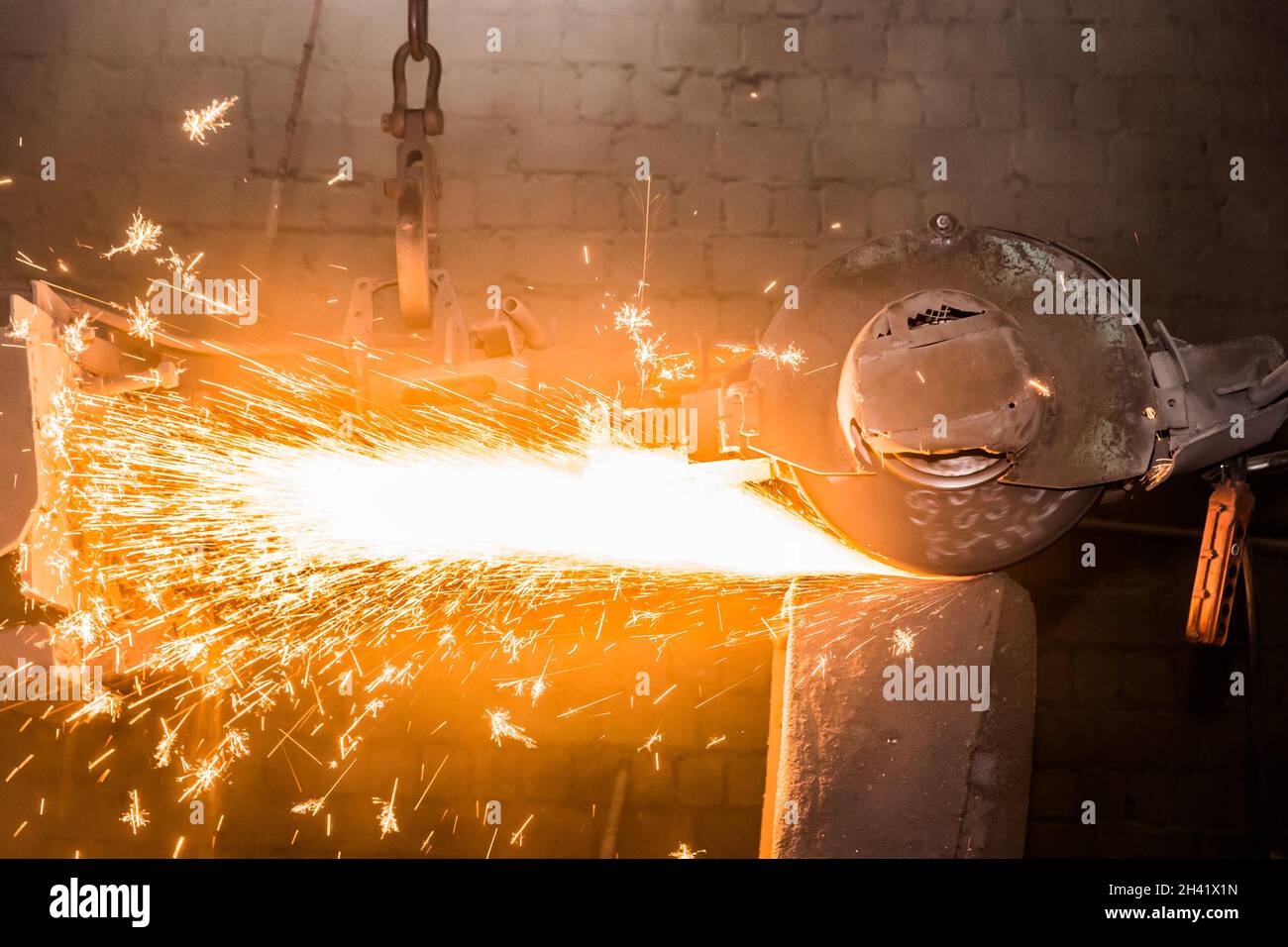 Heavy grinding equipment suspended on a chain with a hook processes and ...