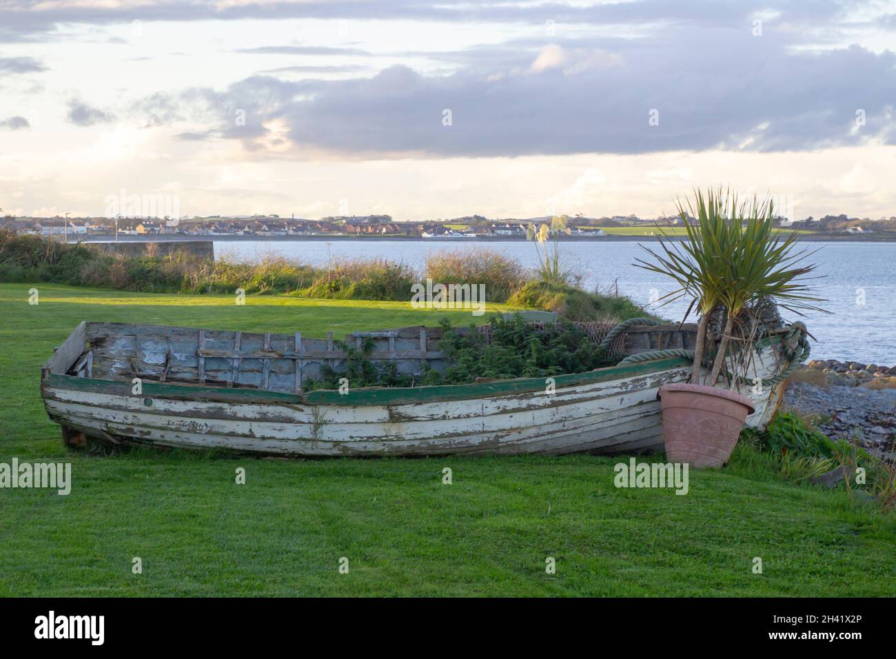 An old derelict clinker built wooden boat used as a garden feature by a ...