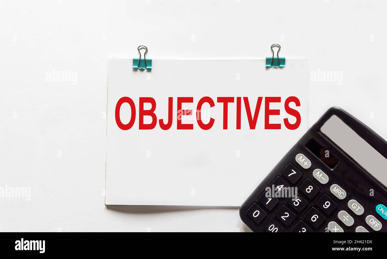 On a white background lies a calculator and a notebook with the word ...