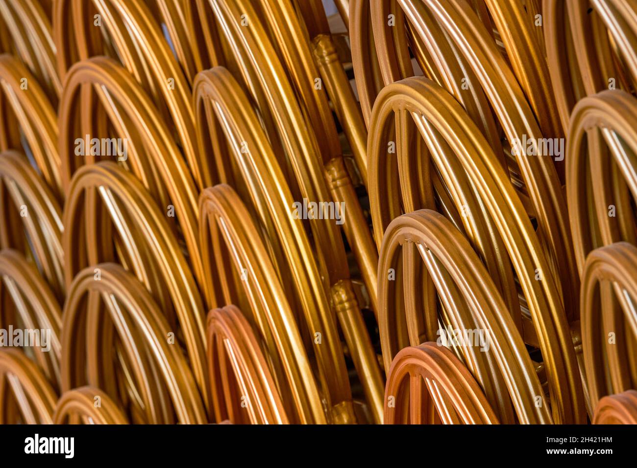 Close-up of stacked golden stools with curved backs Stock Photo - Alamy