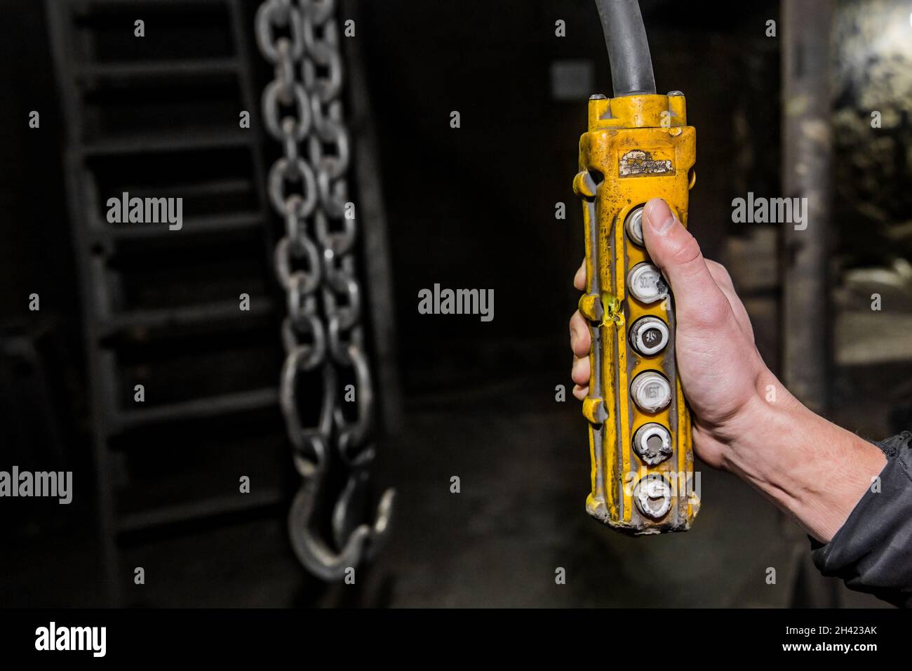 The hand of a worker in overalls holds a panel control panel with a ...