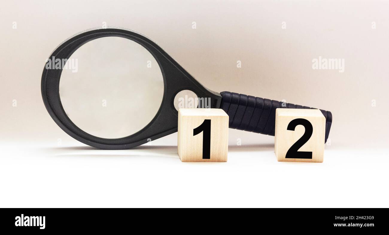 Numbers 1 and 2 on wooden cubes and white background with magnifier ...