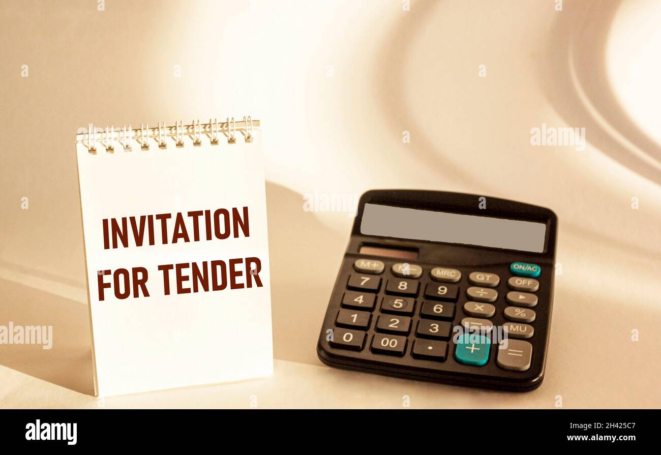 Notepad with the text INVITATION TO TENDER. There is a calculator on a ...