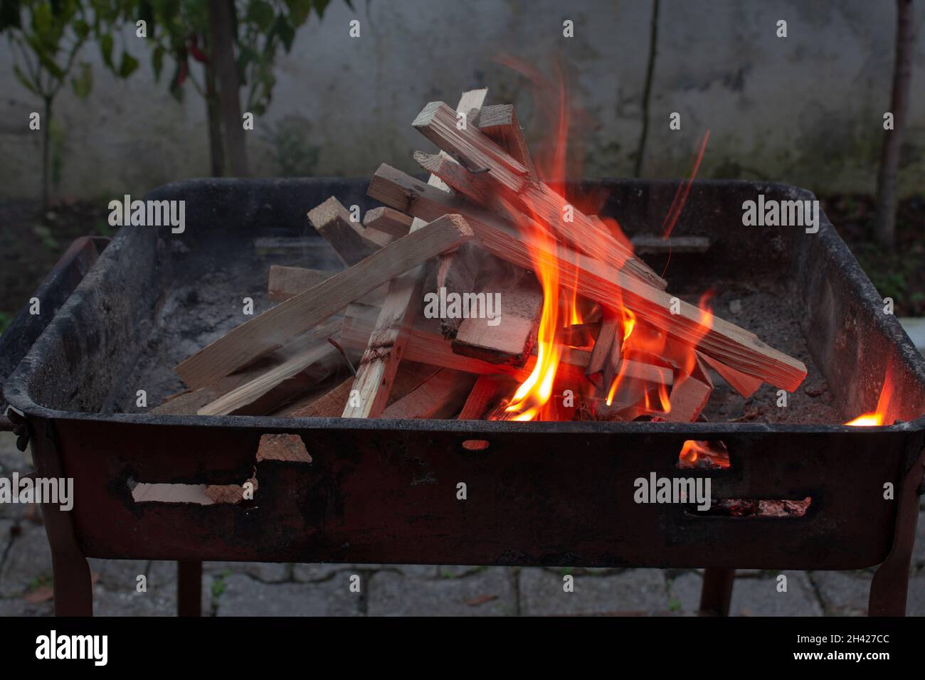 Stacked wooden pieces in a grill burning in orange fire. Preparation ...