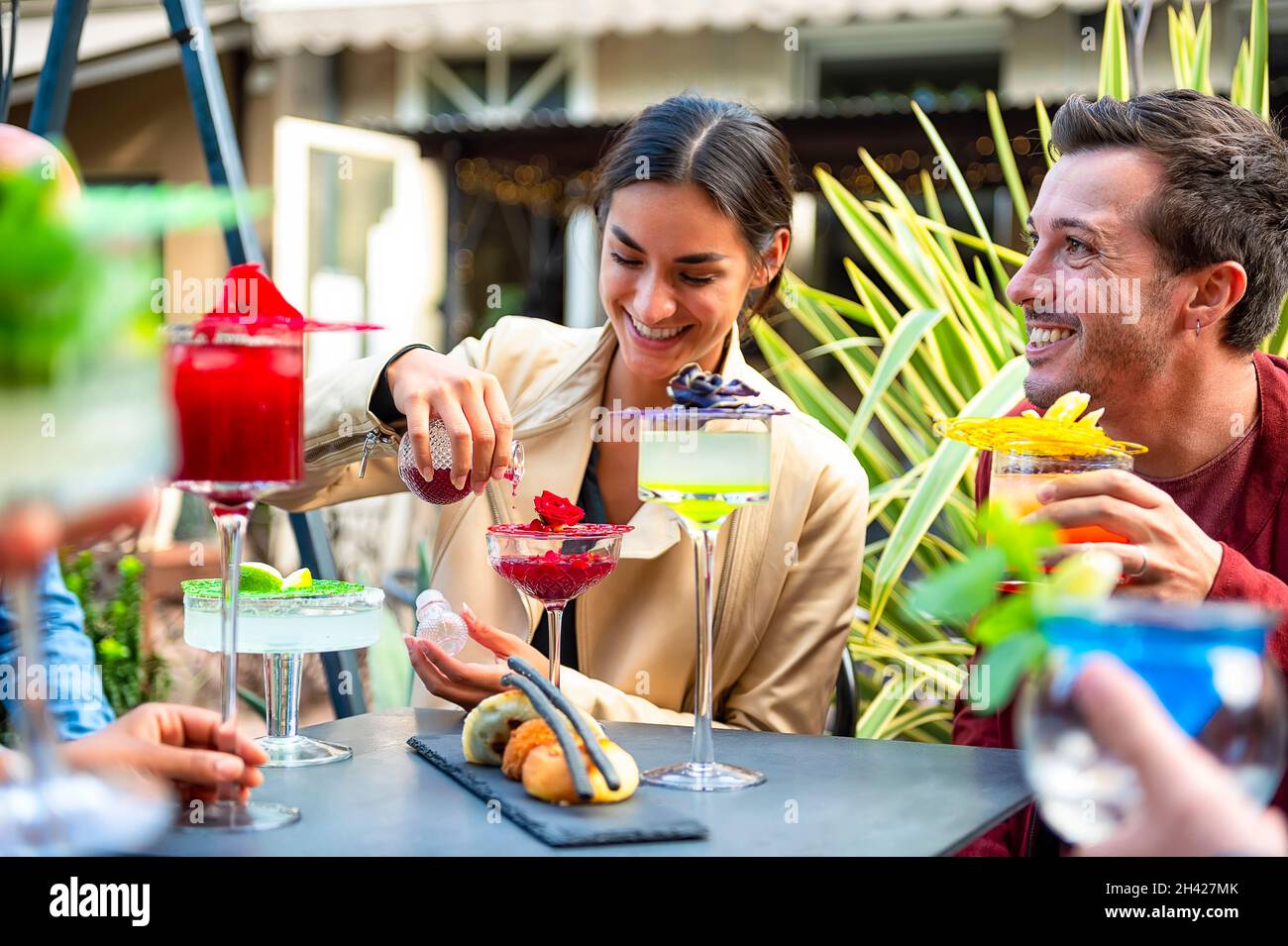 Group friends having fun drinking colored drinks sitting in bar ...