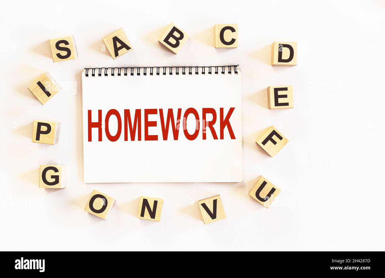 Text HOMEWORK, on notepad and white background, around are wooden cubes ...