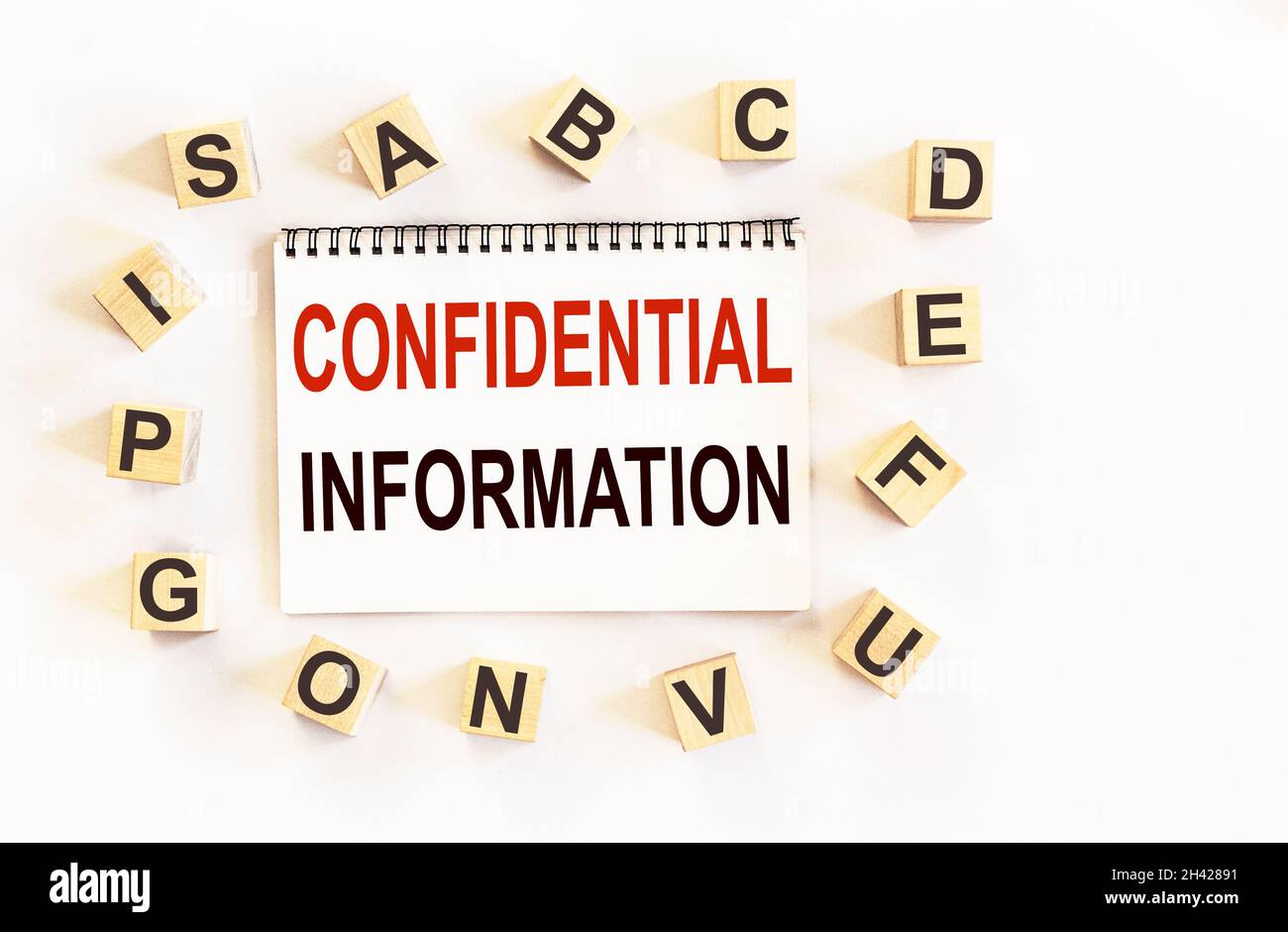 CONFIDENTIAL INFORMATION is written on a notebook next to wooden cubes ...