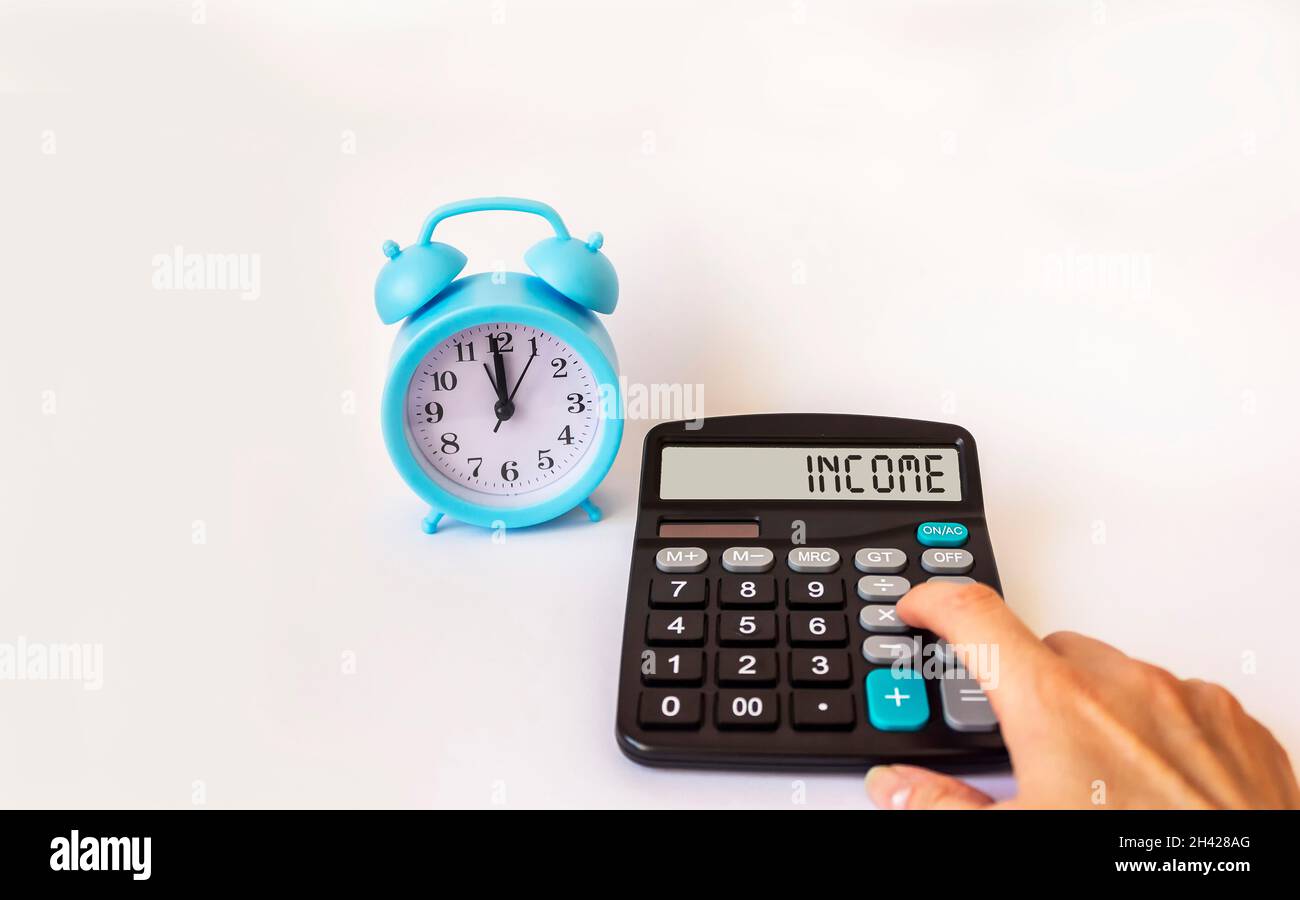 A woman's hand presses on a calculator, on the display of which the ...