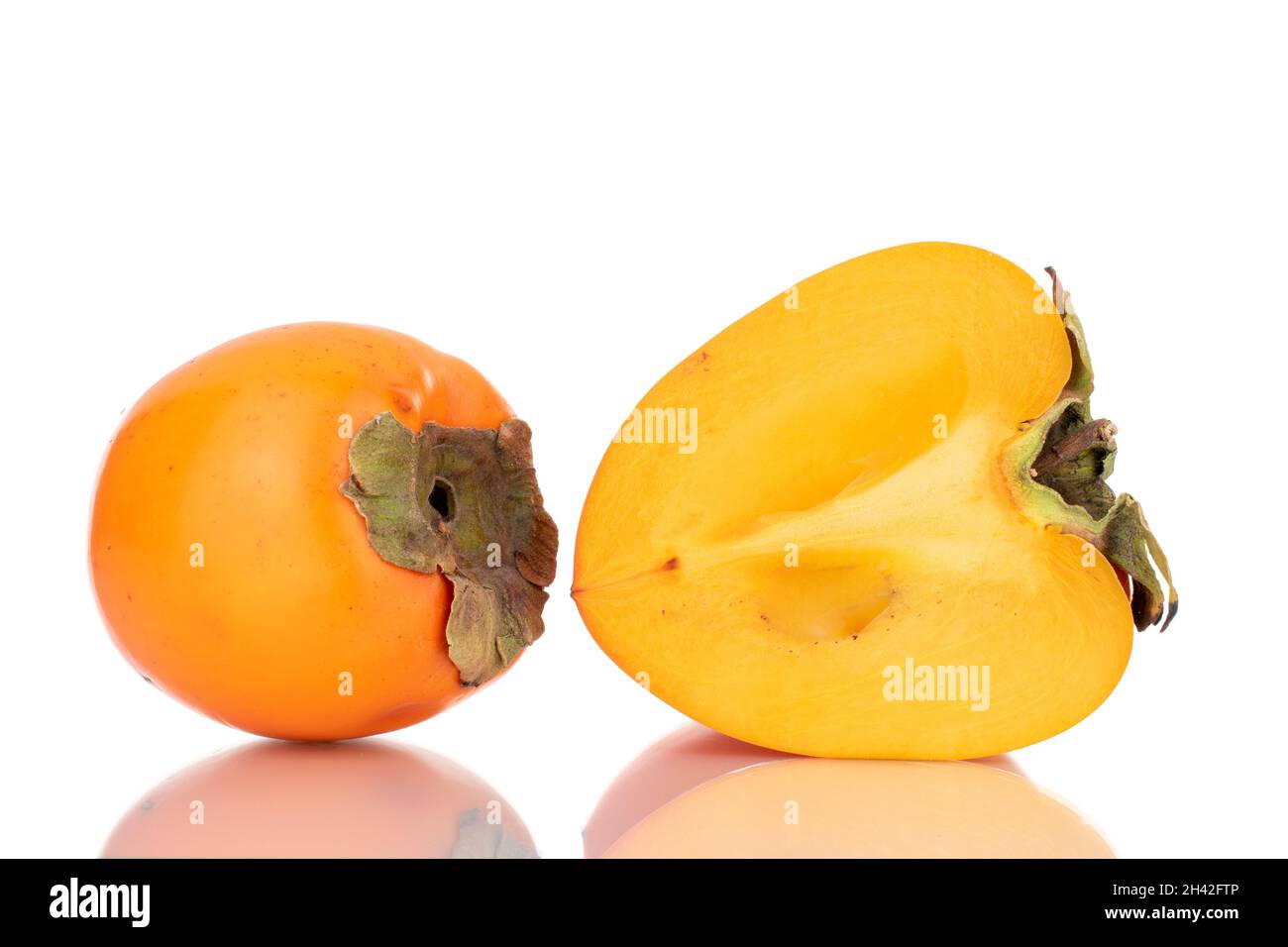 One whole and one half sweet organic persimmon, close-up, isolated on ...