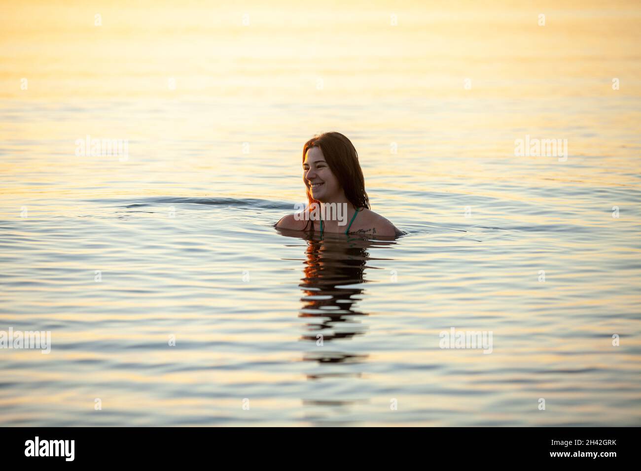 A young Scottish woman cold water swimming at sunrise in the sea at ...