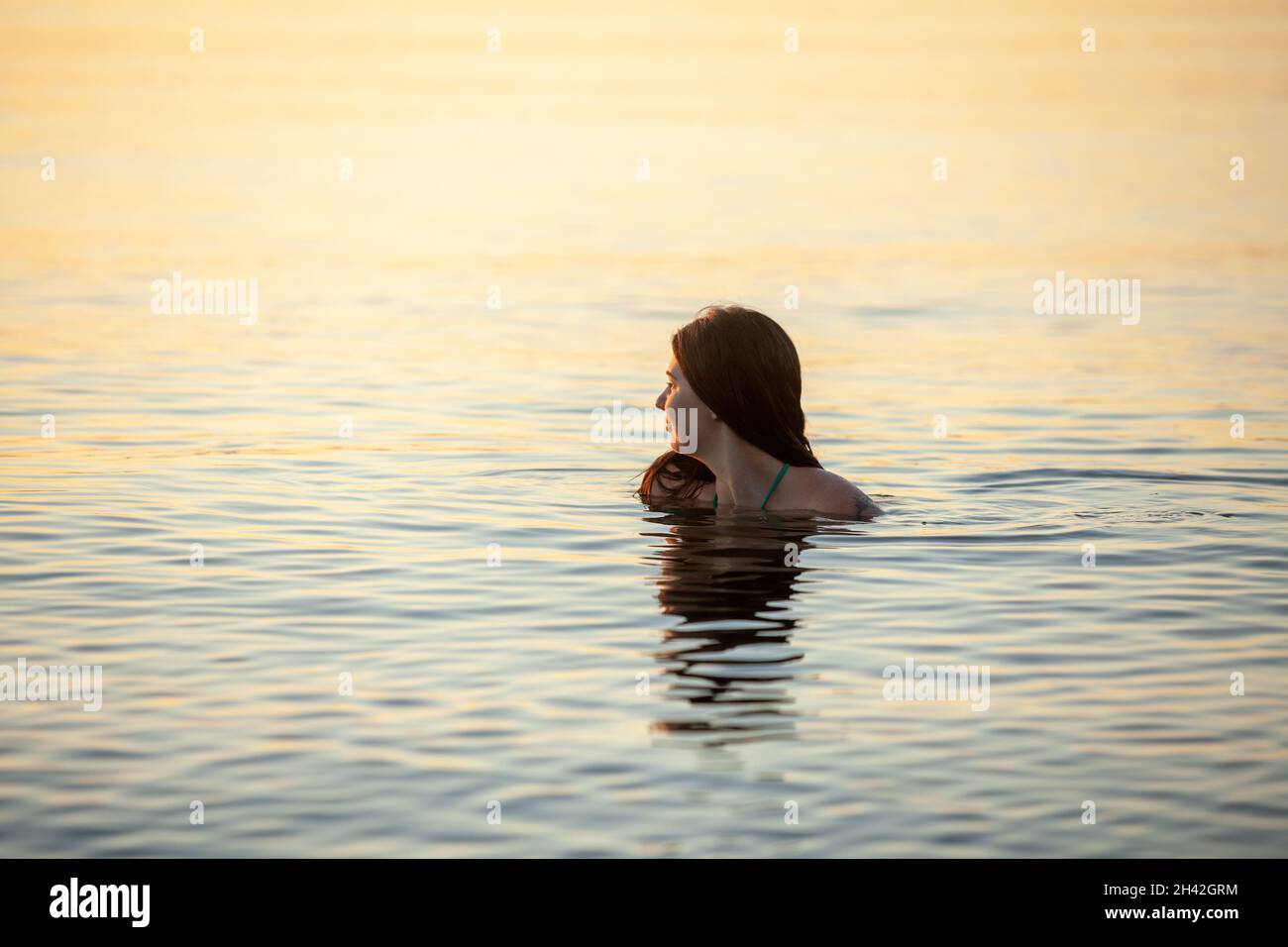 A young Scottish woman cold water swimming at sunrise in the sea at ...