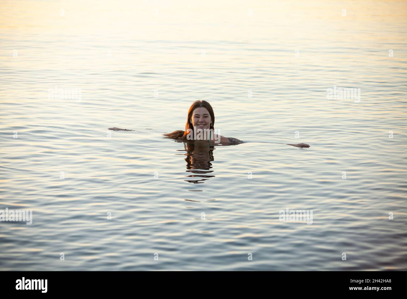 A young Scottish woman cold water swimming at sunrise in the sea at ...