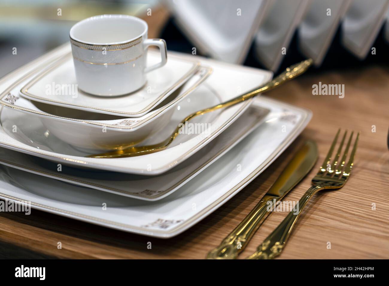 Table setting: white plates and cutlery set on wood background. Table ...