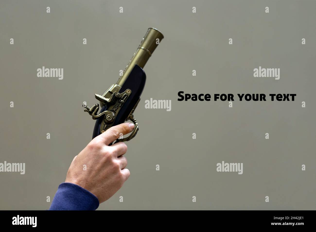 male hand holding plastic toy gun on grey background. Pirate musket ...