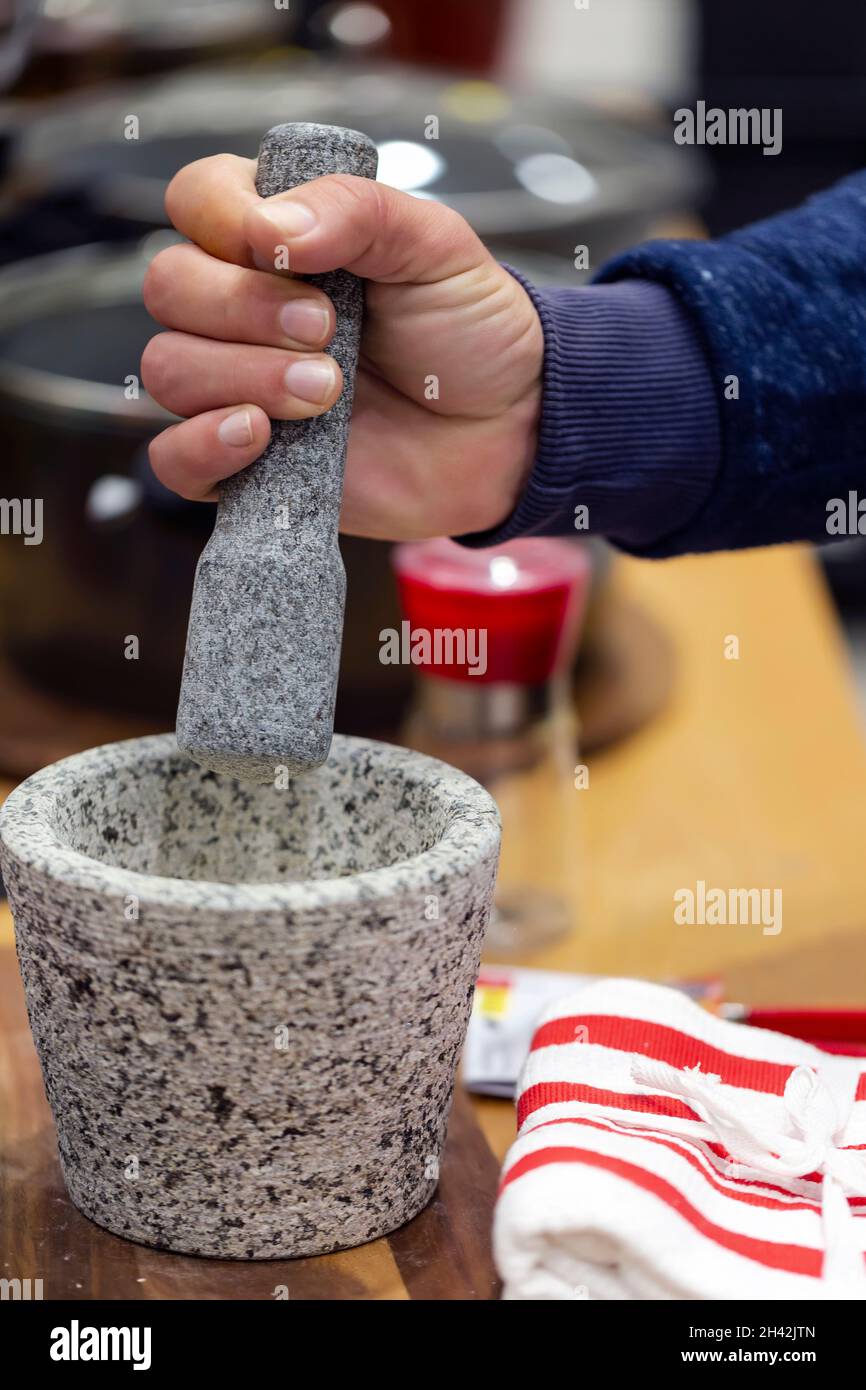 a stone Mortar with spices and pestle in hands at kitchen table, Man ...