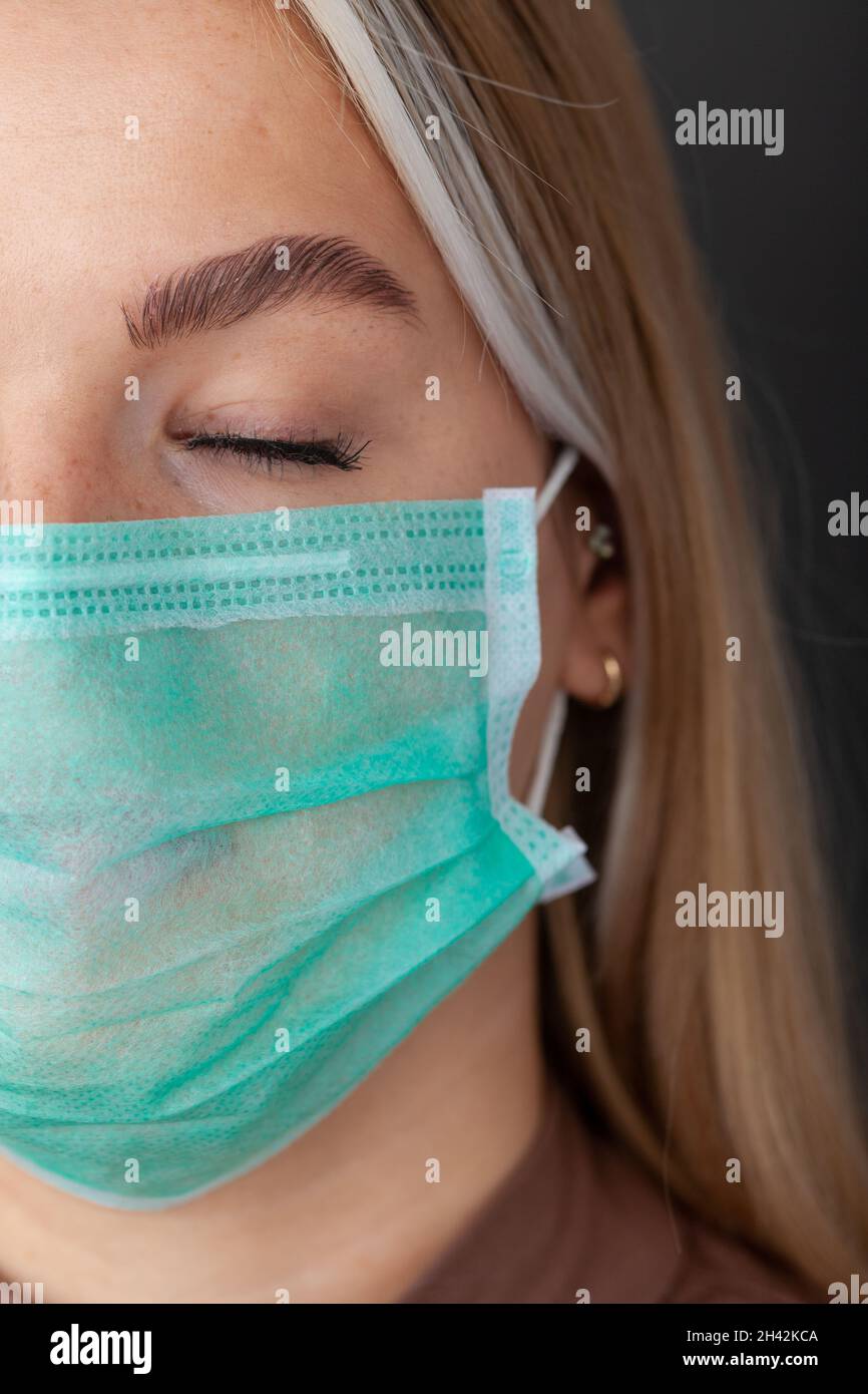 A close up a woman's face wearing a face mask with her eyes closed ...