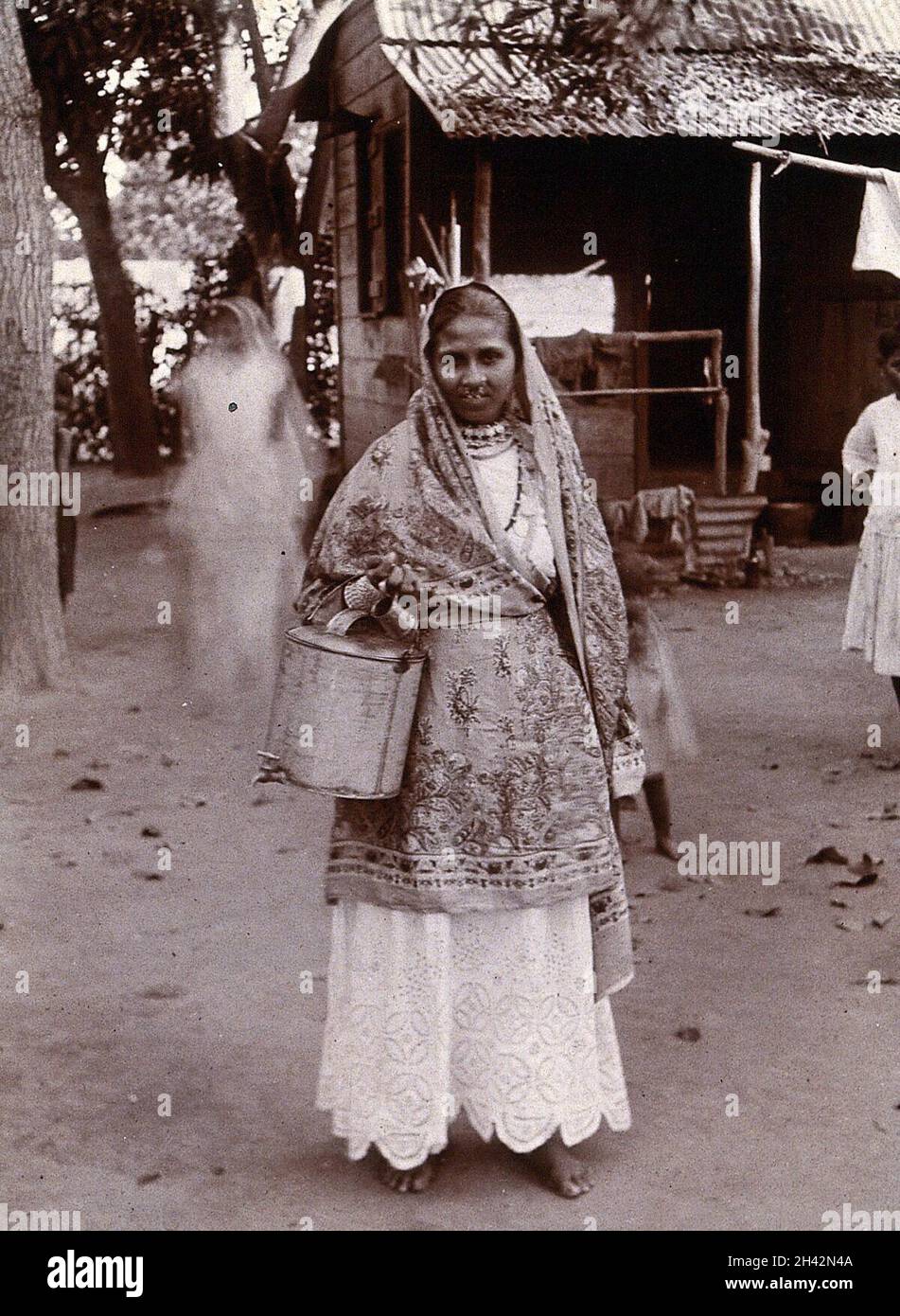 Trinidadian woman in traditional costume carrying a metal milk pail ...
