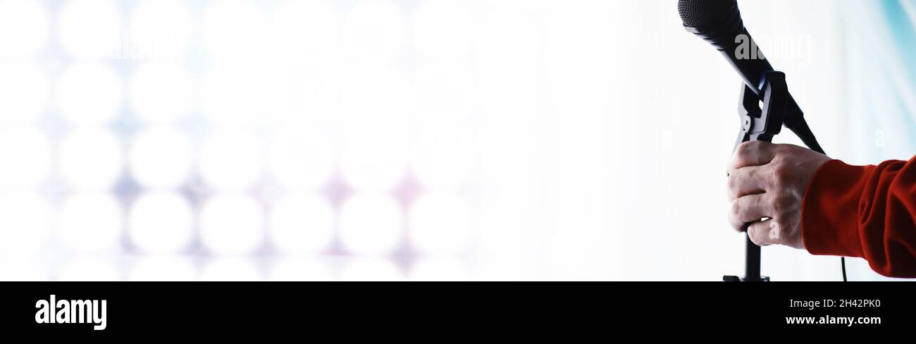 Stand with a microphone. Man holds hands a microphone on tripod ...