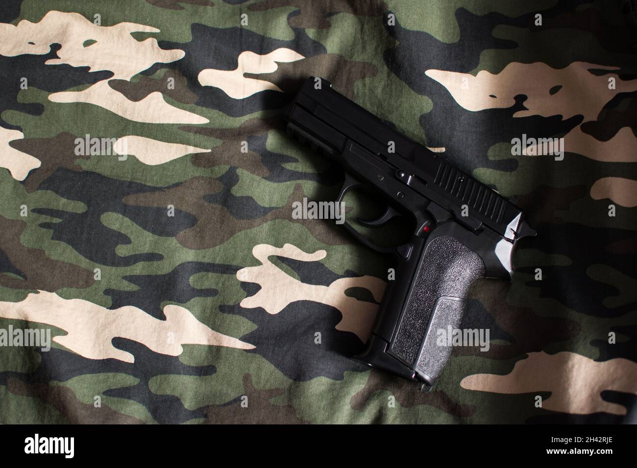 Black handgun on military camouflage green, brown, beige and black ...