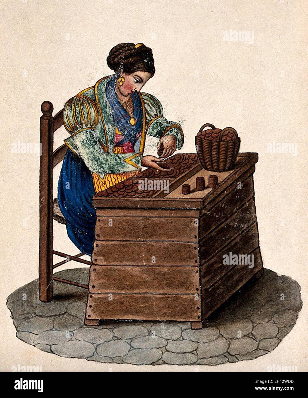 A woman sits at a wooden box counting money out of a basket onto a tray ...