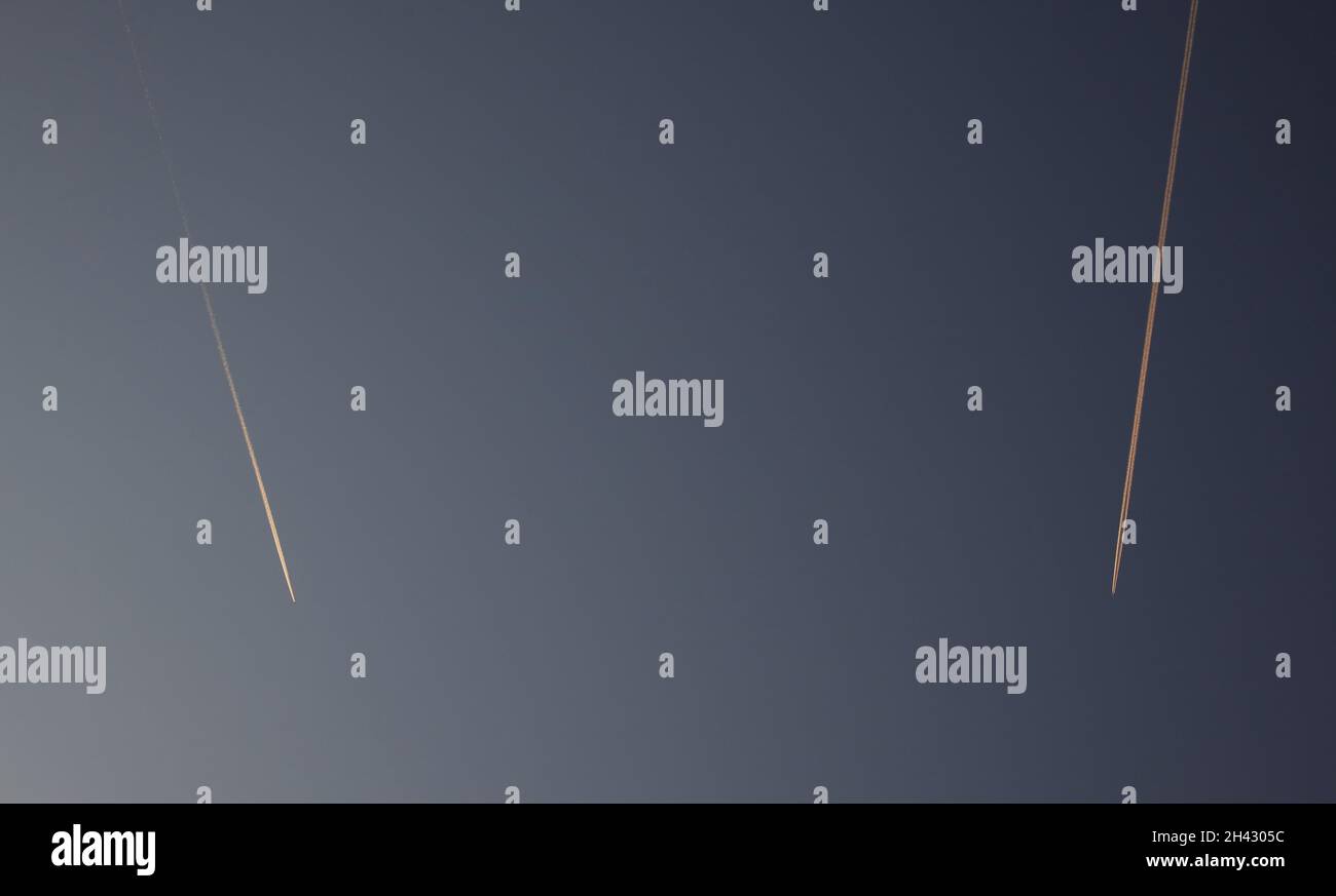Contrails of two airplanes seen in the early morning sky Stock Photo ...