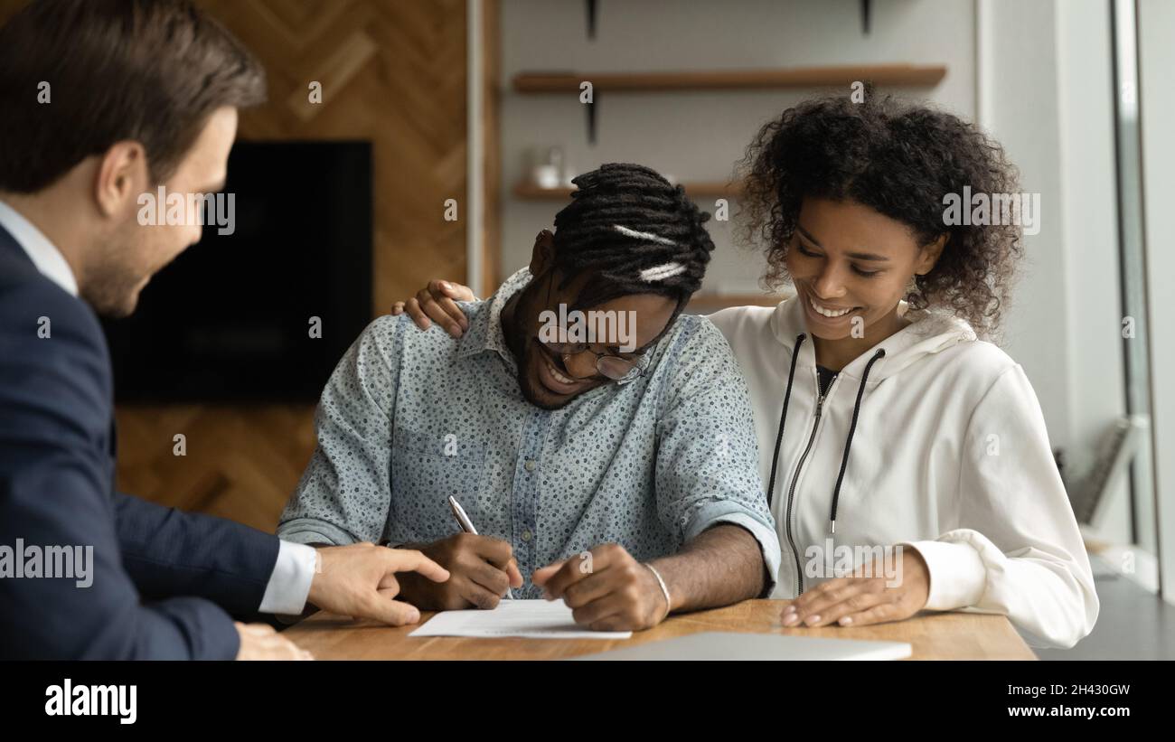 Happy young mixed race clients signing contract with lawyer Stock Photo ...