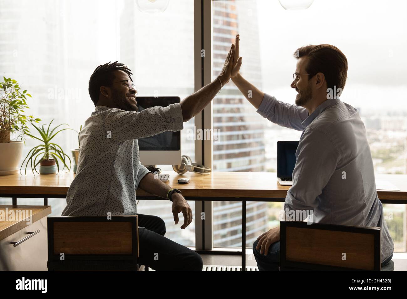 Happy two diverse male employees giving high five Stock Photo - Alamy