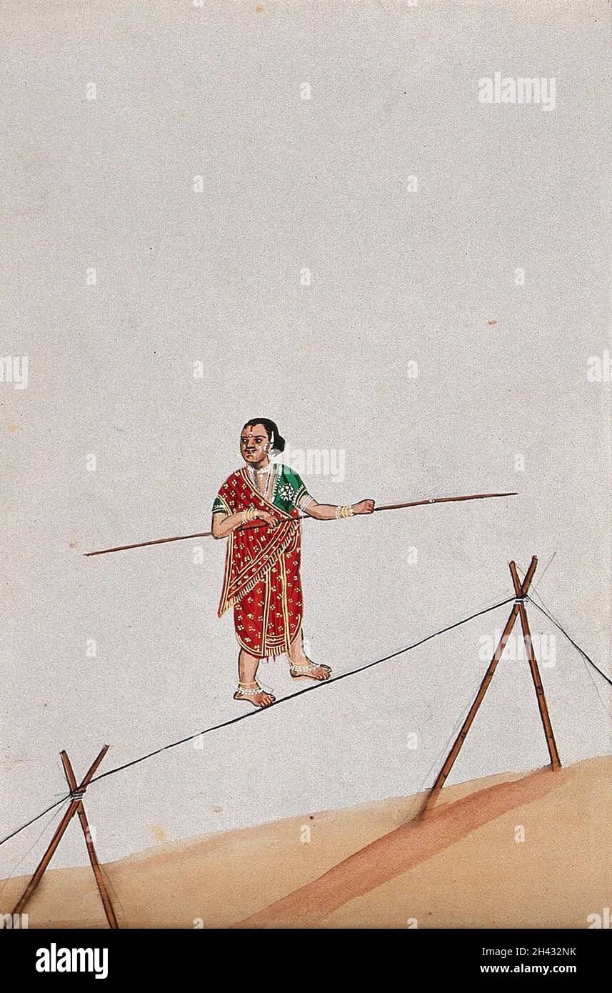 A woman acrobat holding a long stick and walking the tight rope ...