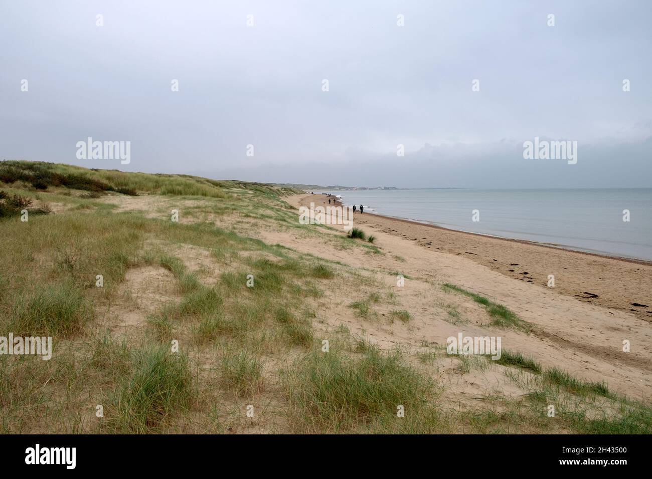 People in the far distance walking along on Camber Sands shore sandy ...