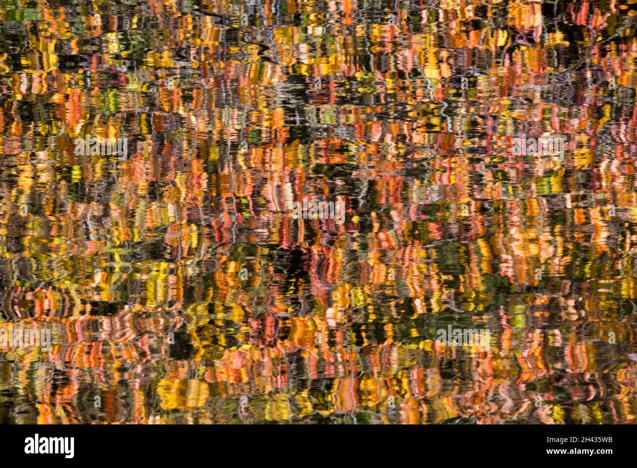 Abstract patterns and colours on the flowing water of a river in Autumn ...