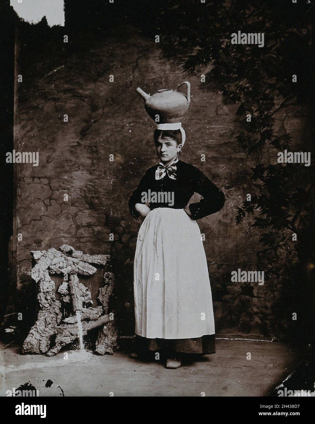 A young Basque woman, with an earthenware jug on her head, posing in ...